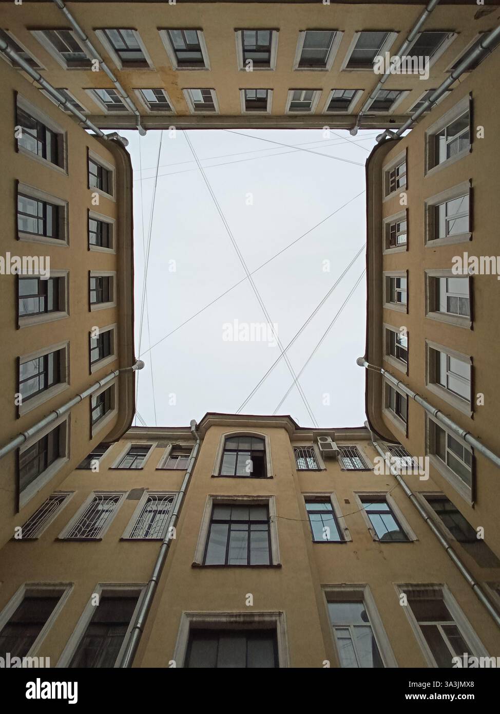 Looking up at a symmetrical courtyard surrounded by old yellow ...