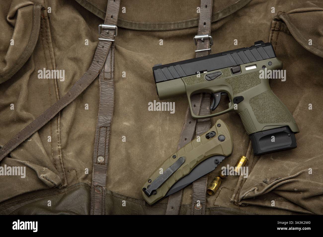 A tactical setup featuring a green and black handgun, a folding knife ...