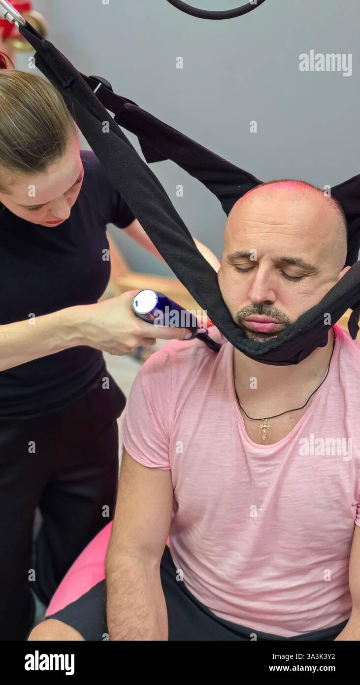 A doctor uses an electric massager for cervical spine treatment and ...