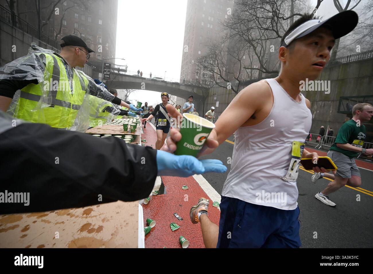 New York, USA. 16th Mar, 2025. A runner grabs a cup of liquid held out ...