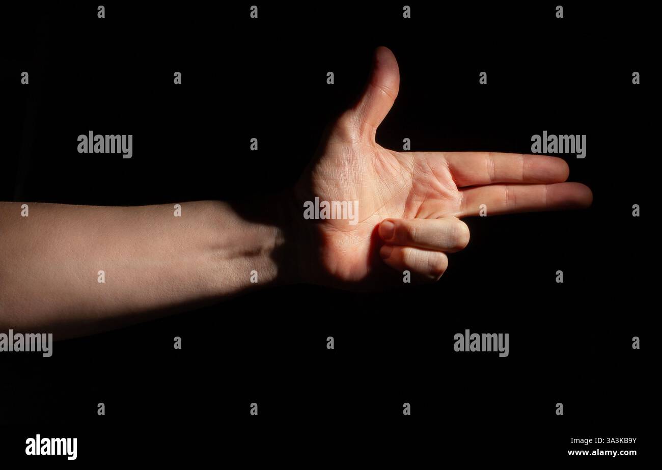 gun finger gesture on black background Stock Photo - Alamy