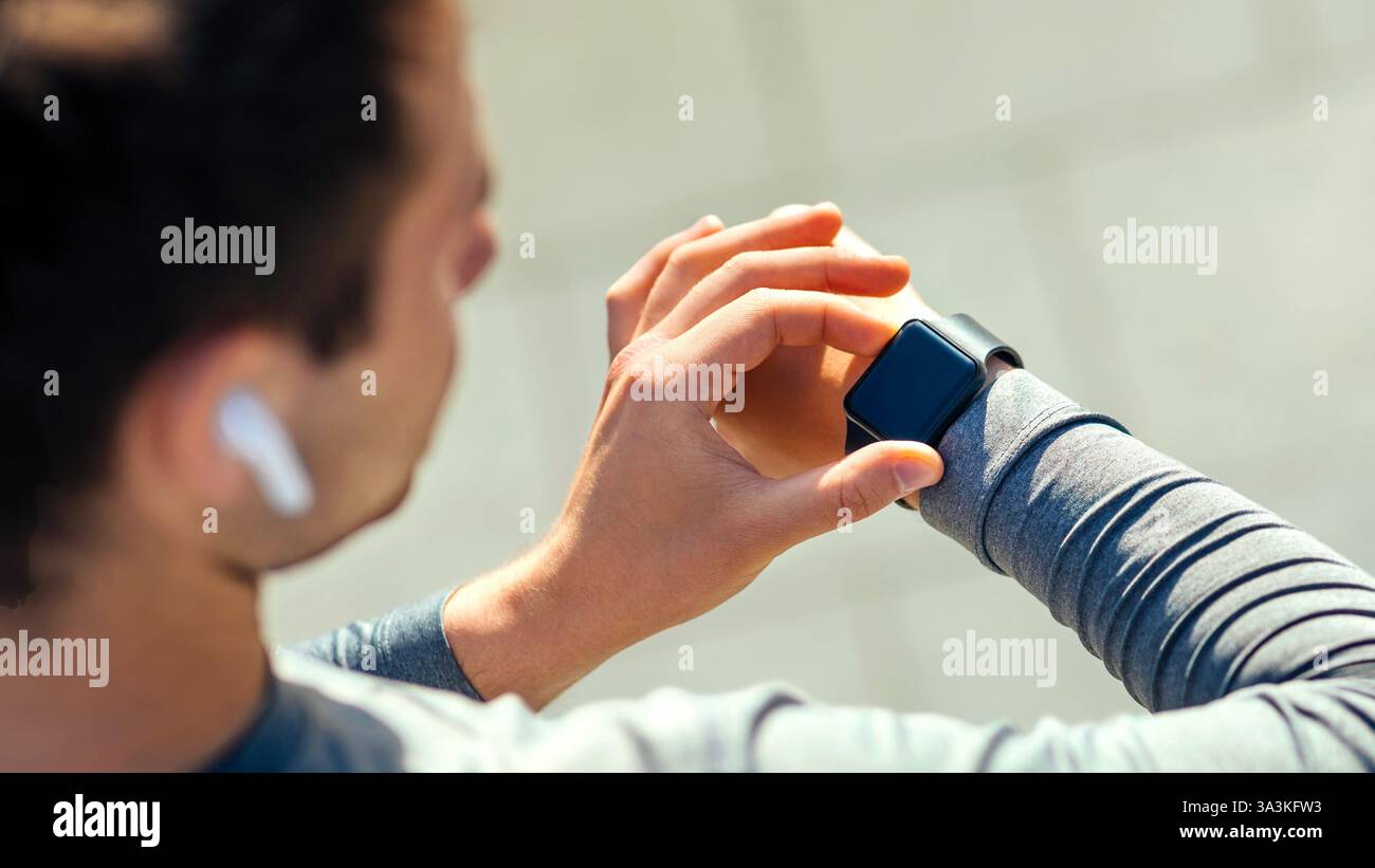 Modern run with handy gadgets. Guy in wireless headphones, stops and ...