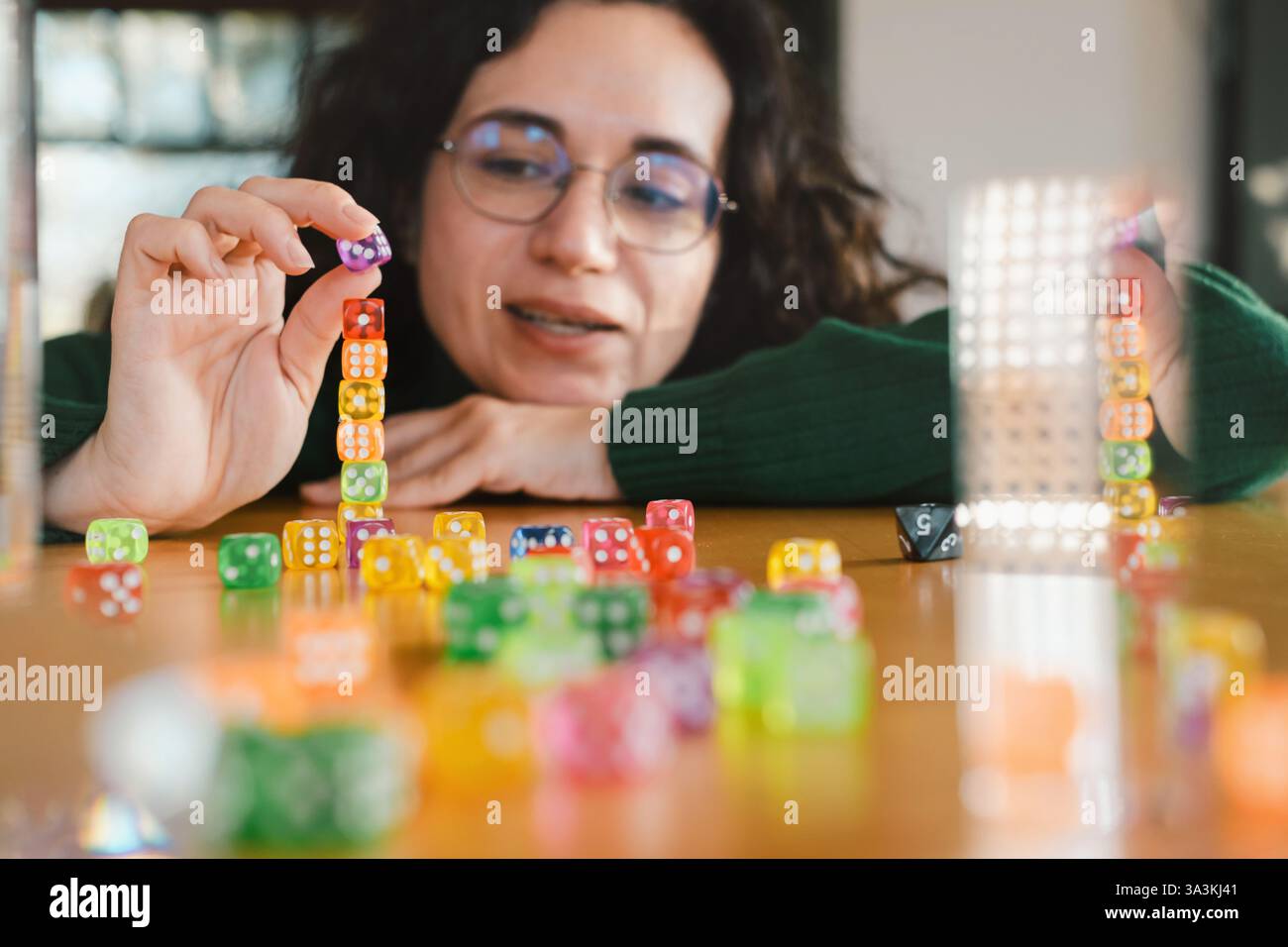 Woman player at her 40s stacking colorful dice during table game night ...