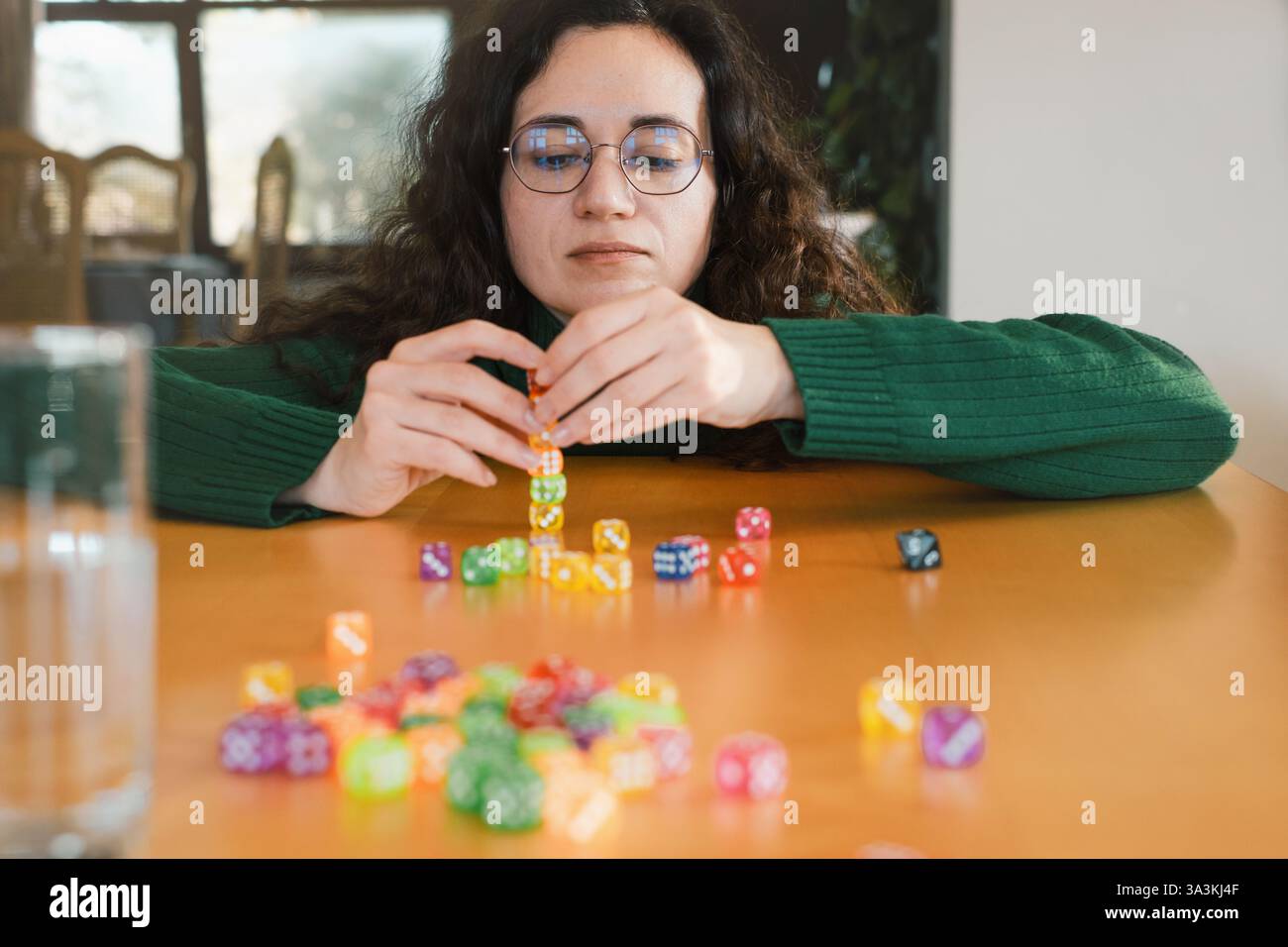 Woman player at her 40s stacking colorful dice during table game night ...