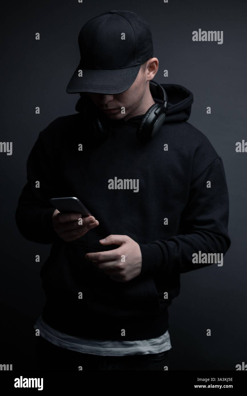 young cool rapper with black hoodie and cap looking down to his ...