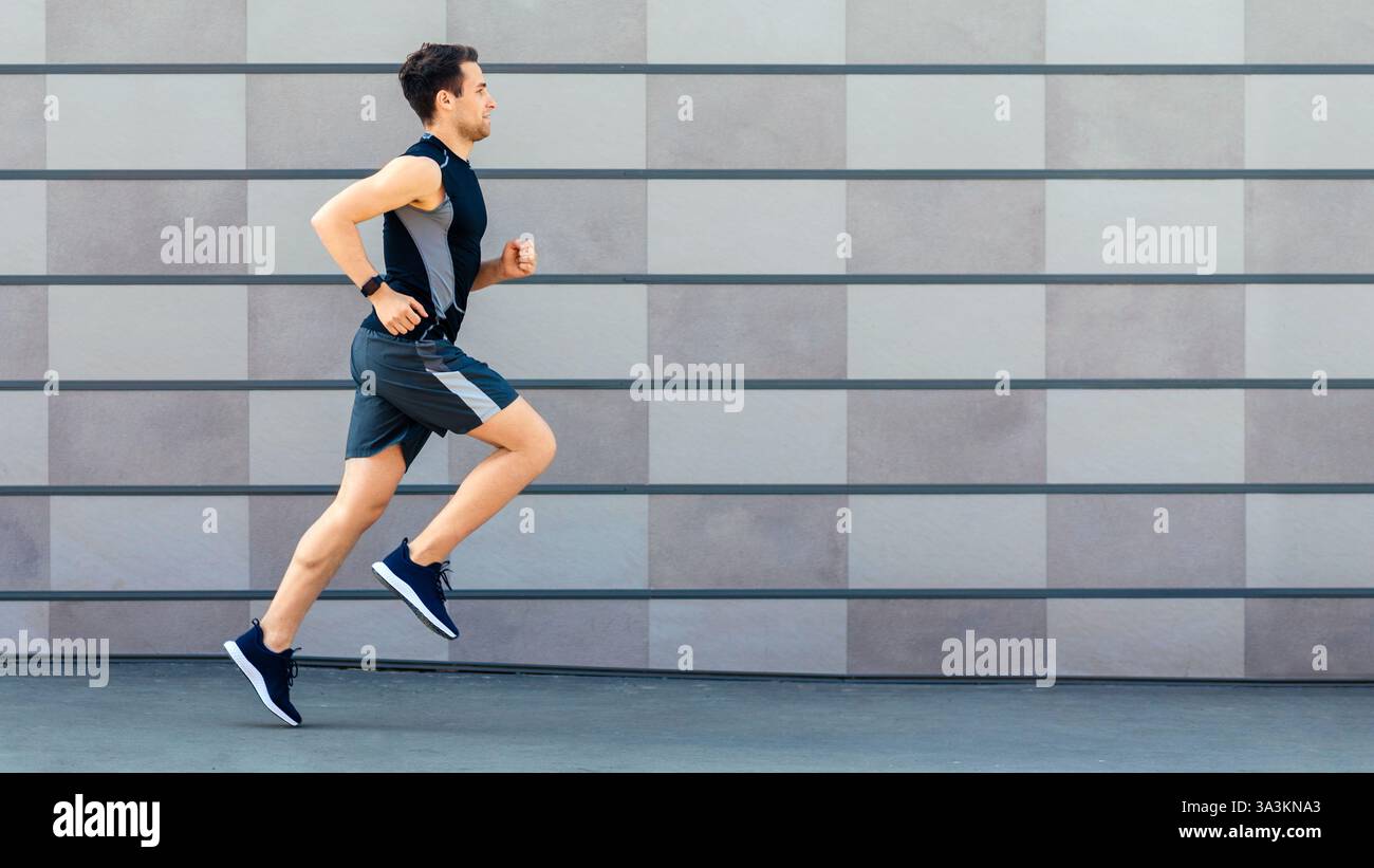 Jogging for health. Man with fitness tracker runs on gray wall ...