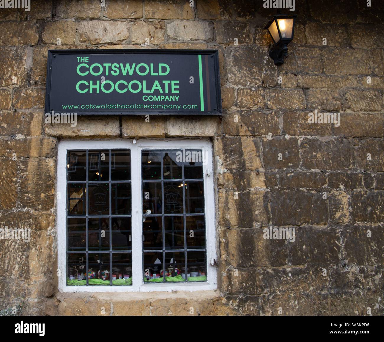 Stone wall with a window beneath a sign for The Cotswold Chocolate ...