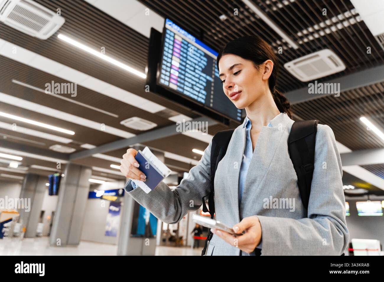 Girl looks at the flight ticket at the airport on flight schedule ...