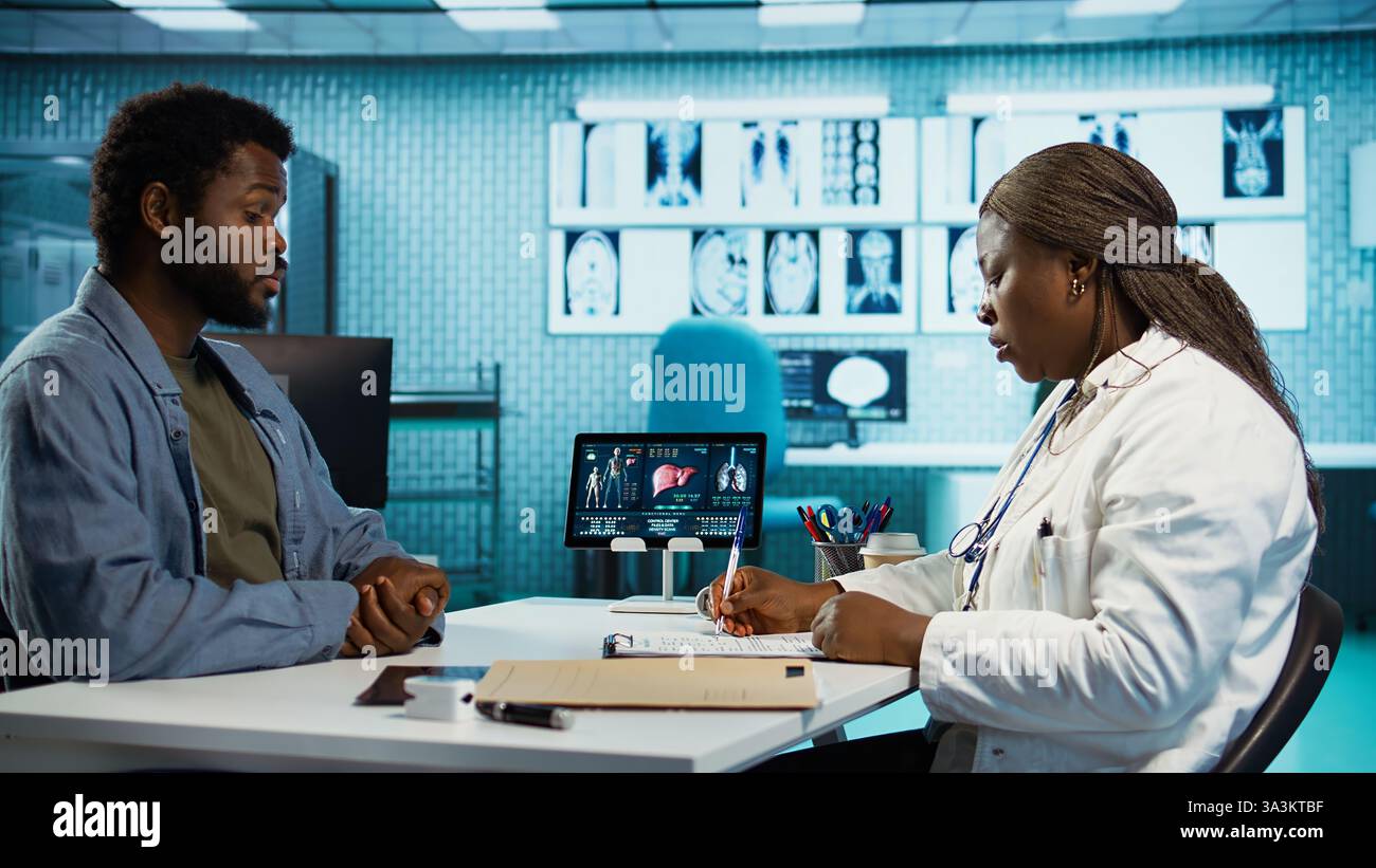 Medic takes notes during routine checkup visit with young man ...