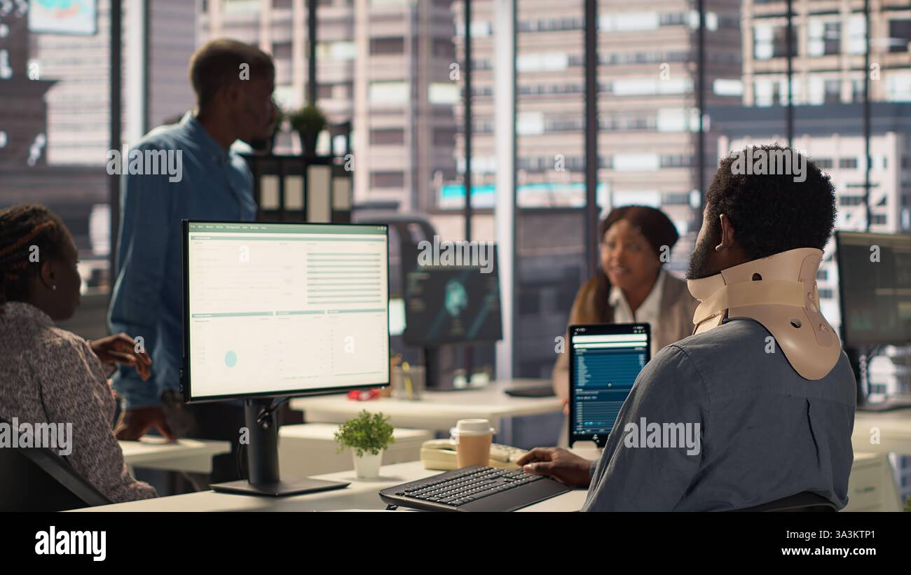 Black businessman struggles to work at the desk with a neck fracture ...