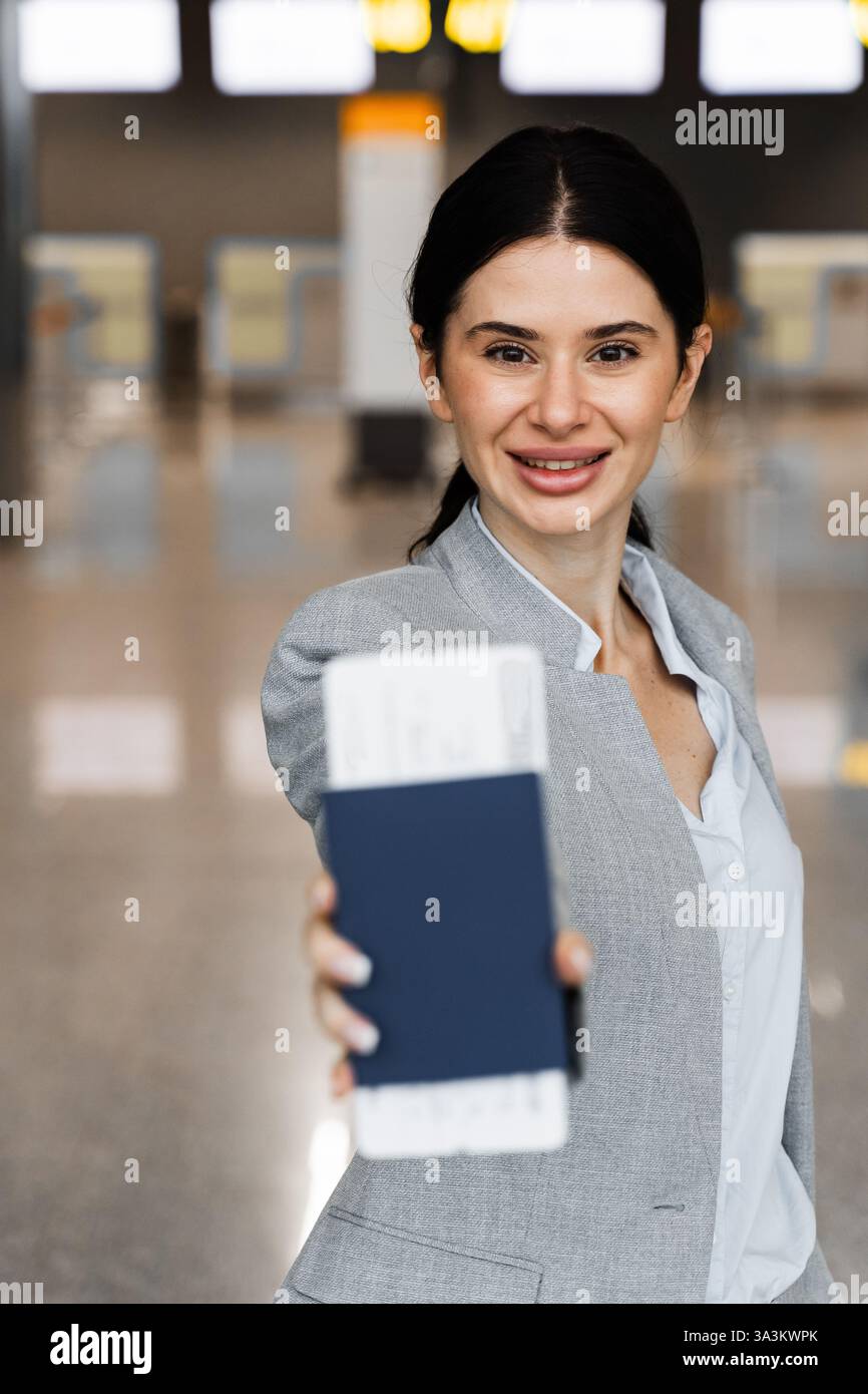 Asian girl traveler is showing ticket and passport at the airport terminal. Excited young woman ...