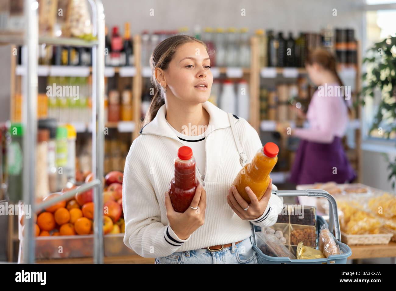 Young woman chooses juices in grocery store Stock Photo - Alamy