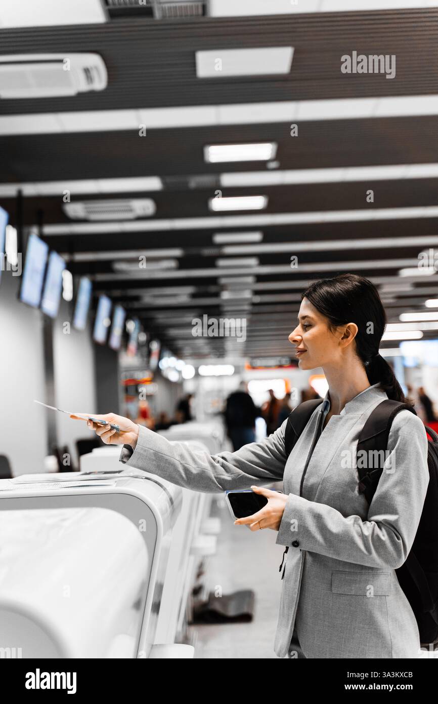 Woman giving boarding pass and passport at the airport check in counter ...