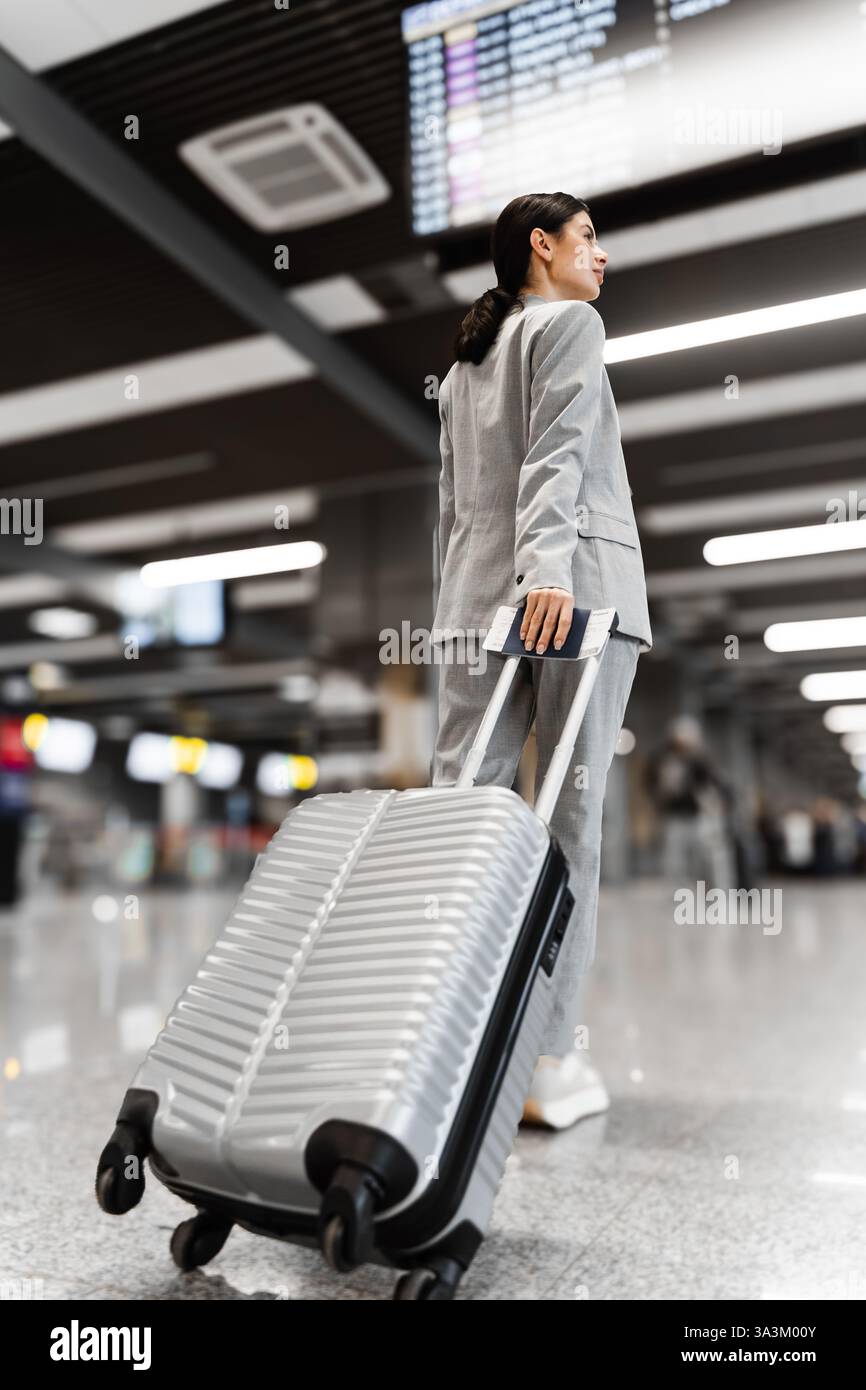 Asian woman looks at the flight schedule in the airport terminal to ...