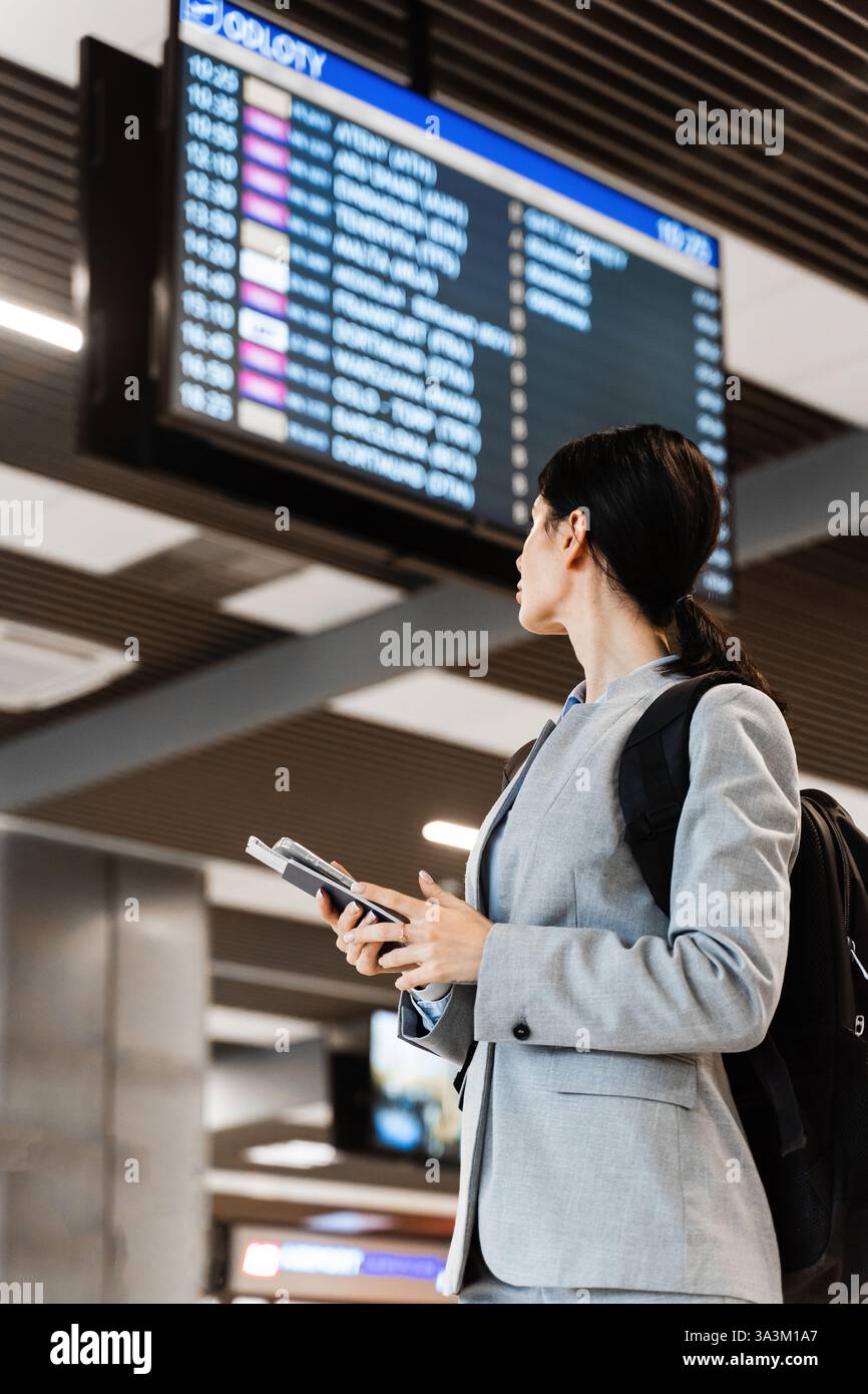Girl looks at the flight ticket at the airport on flight schedule ...