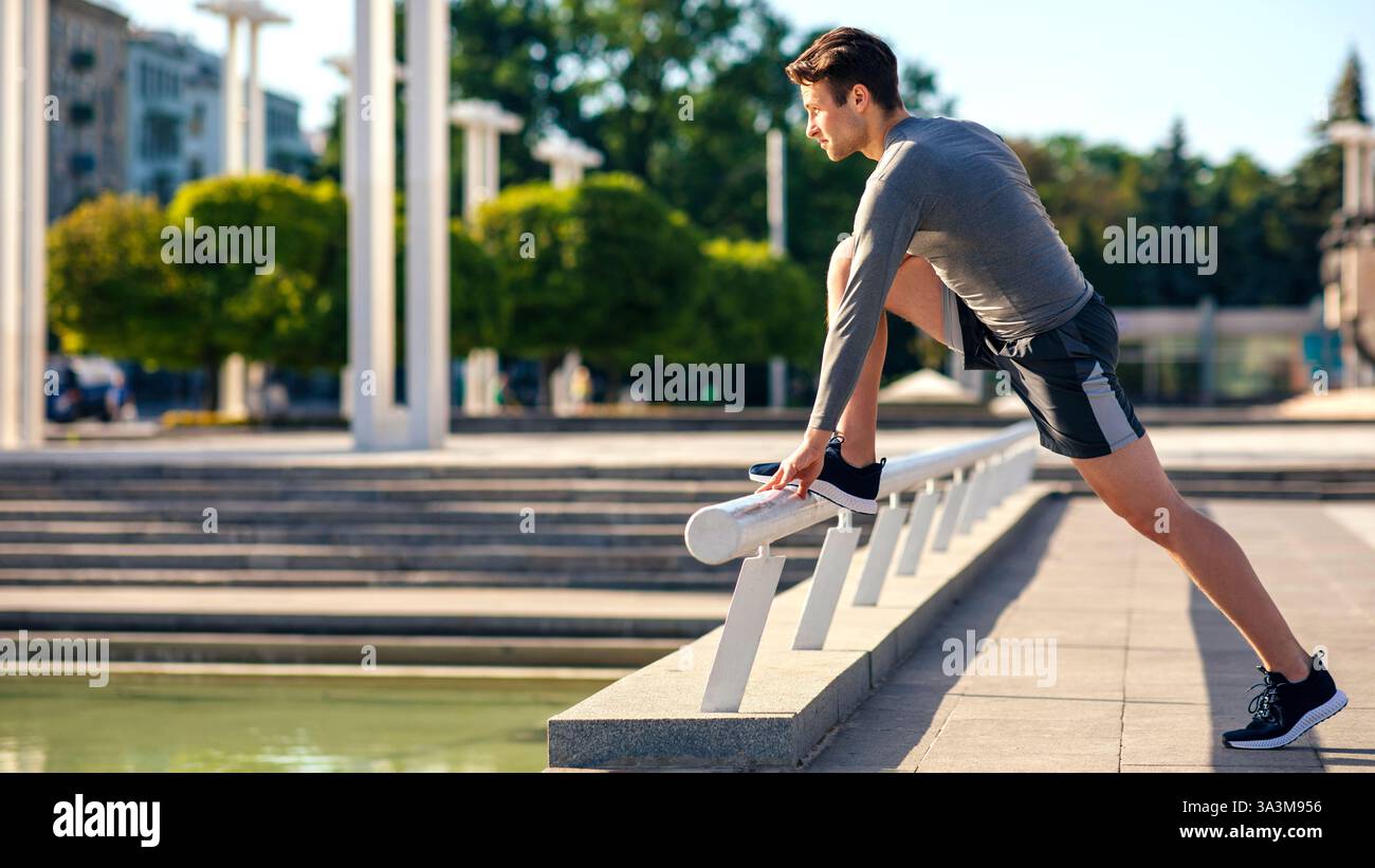 Morning stretching. Guy puts his foot on railing and does exercises Stock Photo - Alamy