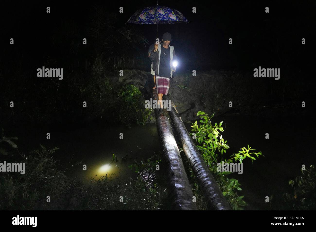 Sudirman, front, and Irfan walk on a makeshift bridge as they inspect ...