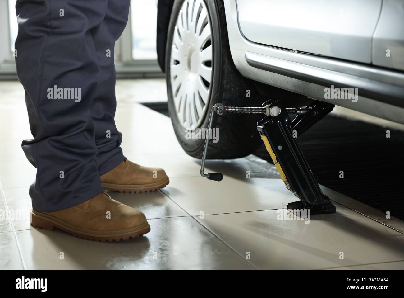 Car lifted by scissor jack. Auto mechanic repairing vehicle at service ...