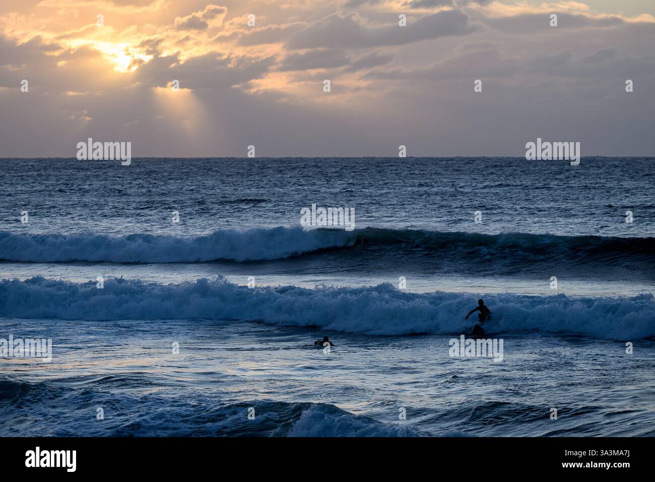 Surfers are seen at sunrise at Cronulla Beach in Sydney, Monday, March ...