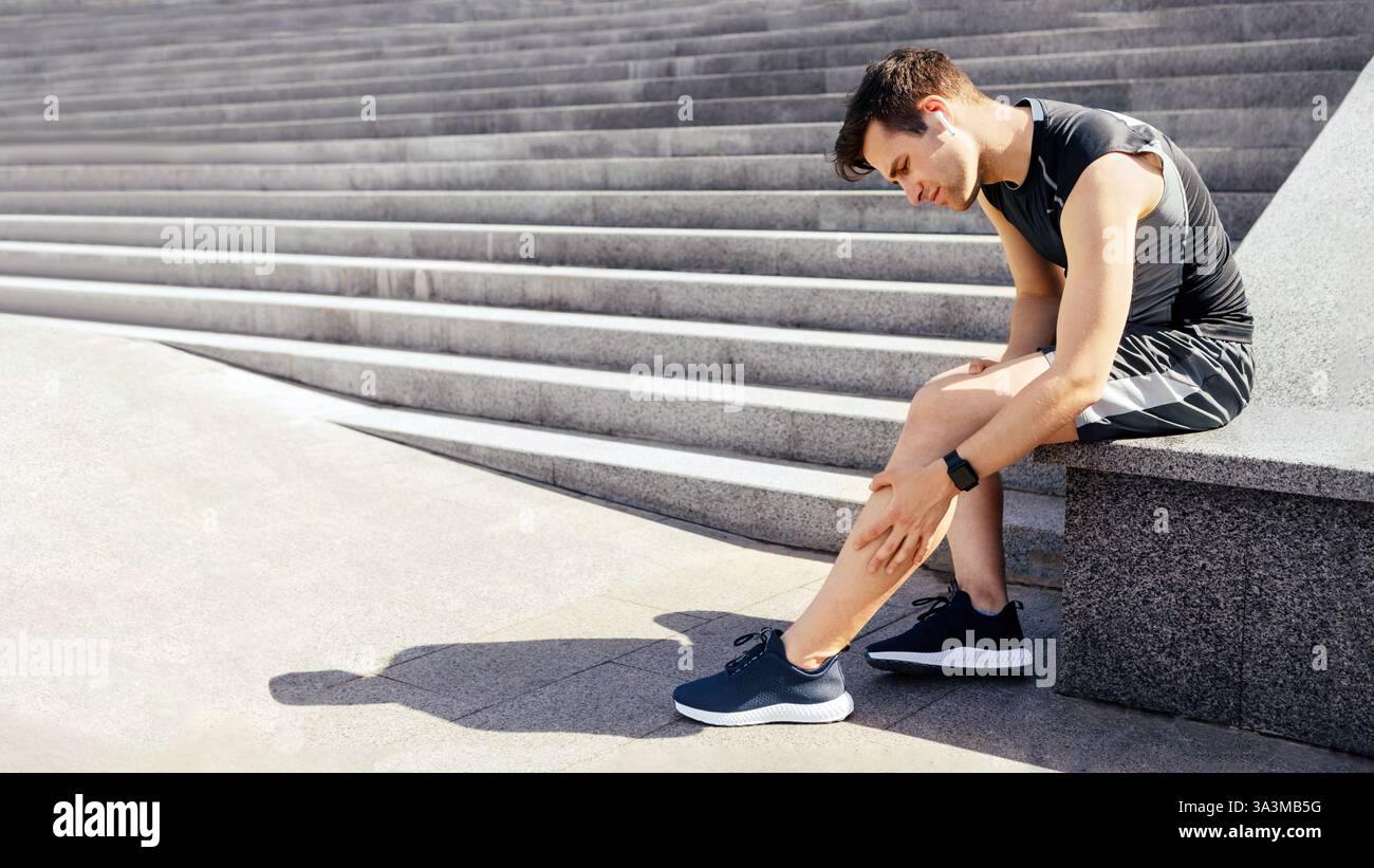 Leg injury. Guy with expression of pain on face, sits and rubs leg ...