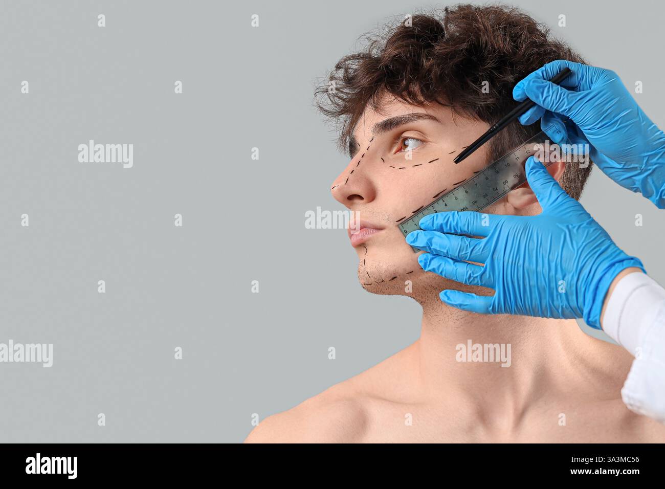 Female plastic surgeon marking man's face on grey background, closeup ...