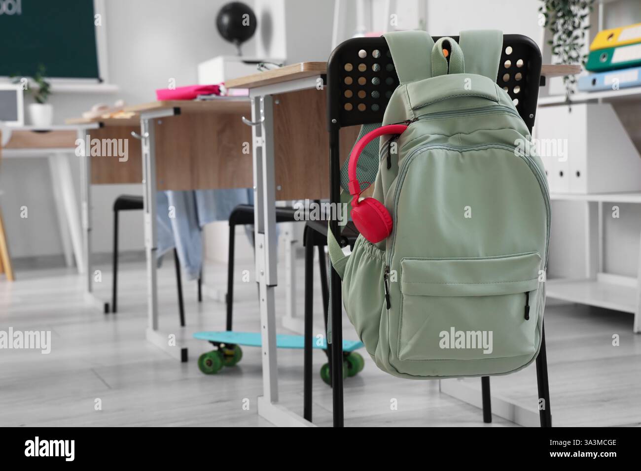 Backpack with headphones hanging on chair in classroom Stock Photo - Alamy