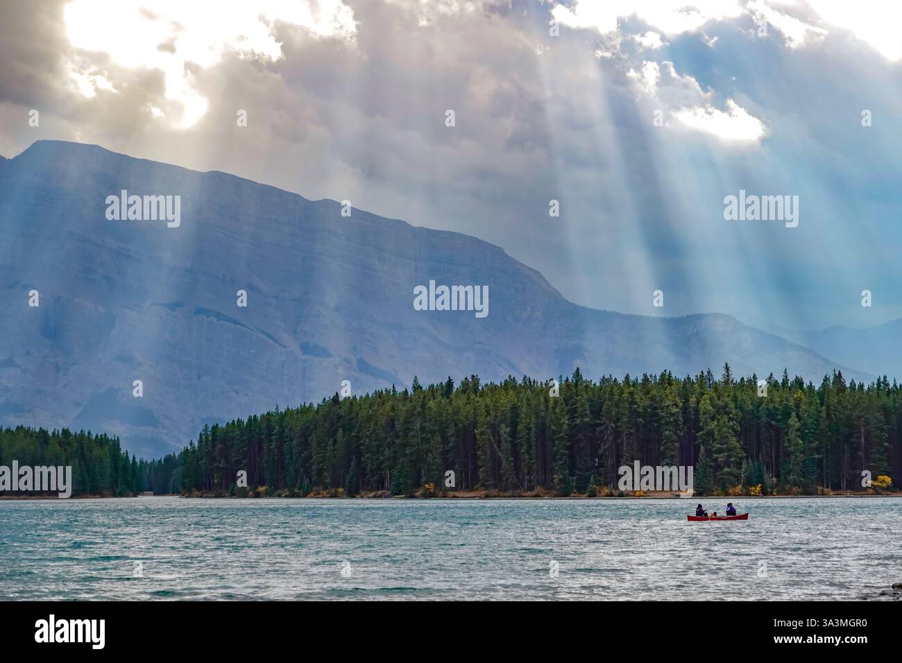 Two Jack Lake Serenity: Mountain Rays and Canoe Vista Stock Photo - Alamy