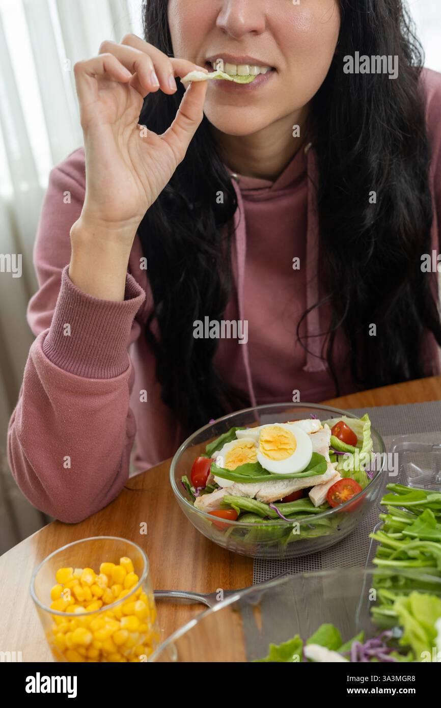 A woman savoring every bite of a vibrant salad with tomato, lettuce ...