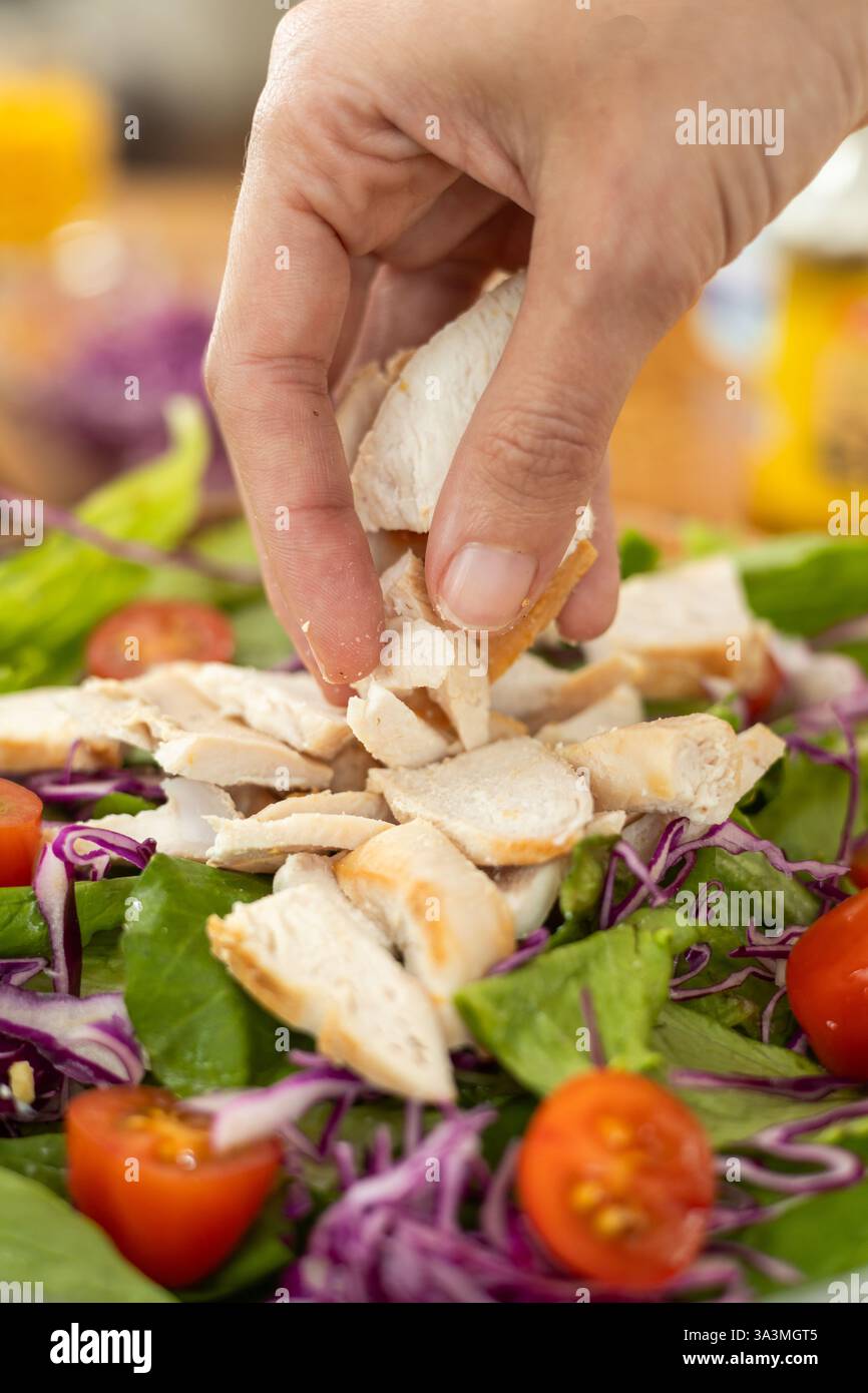 A hand elegantly selecting tender, well-seasoned grilled chicken strips ...