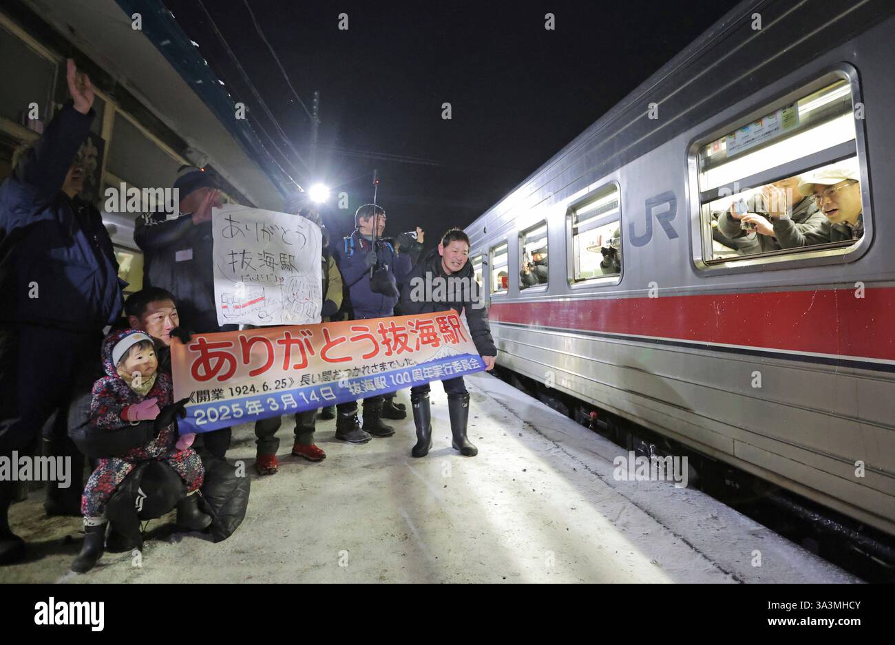 Railway buffs see off the last train with a banner, saying "Thank you ...