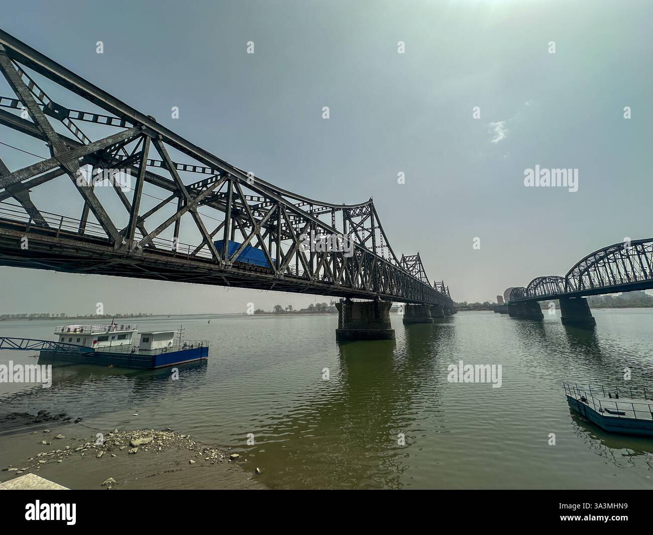 Trucks cross into North Korea from China on the bridge at Dandong China ...