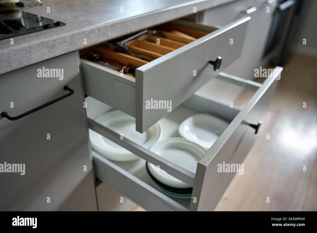 Modern kitchen with dishes and cutlery in open drawers. Contemporary ...