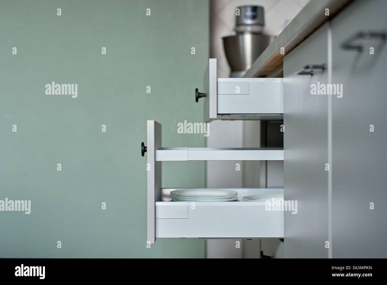 Modern kitchen with dishes and cutlery in open drawers. Contemporary ...