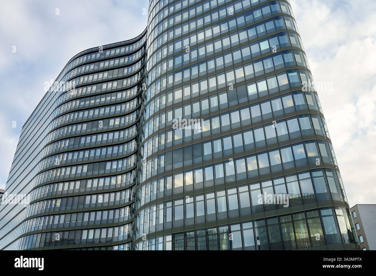 Modern glass office building with curved facade reflecting sky. Exterior of contemporary high ...