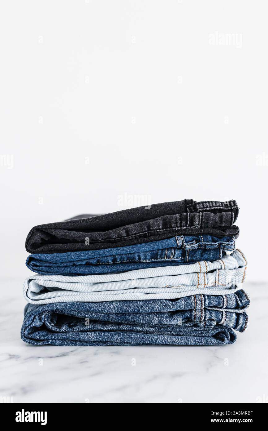 pile of jeans in different color denim fabric neatly folded and piled ...