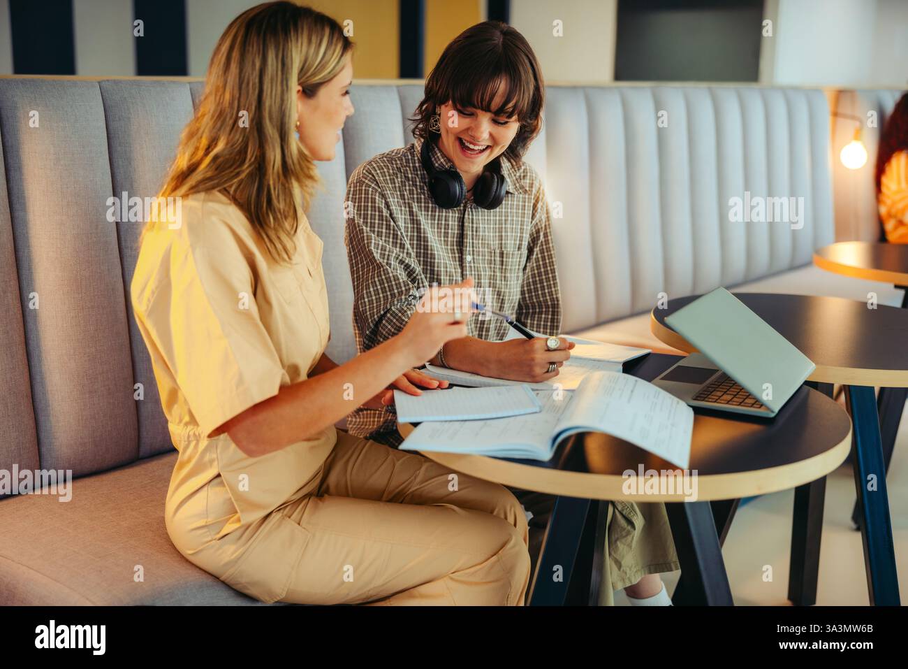 Two joyful college classmates share a moment of laughter while studying ...