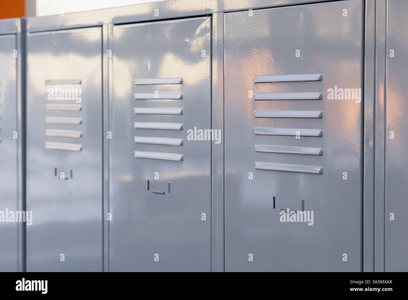 Polished metal lockers line the wall of a bustling school corridor ...