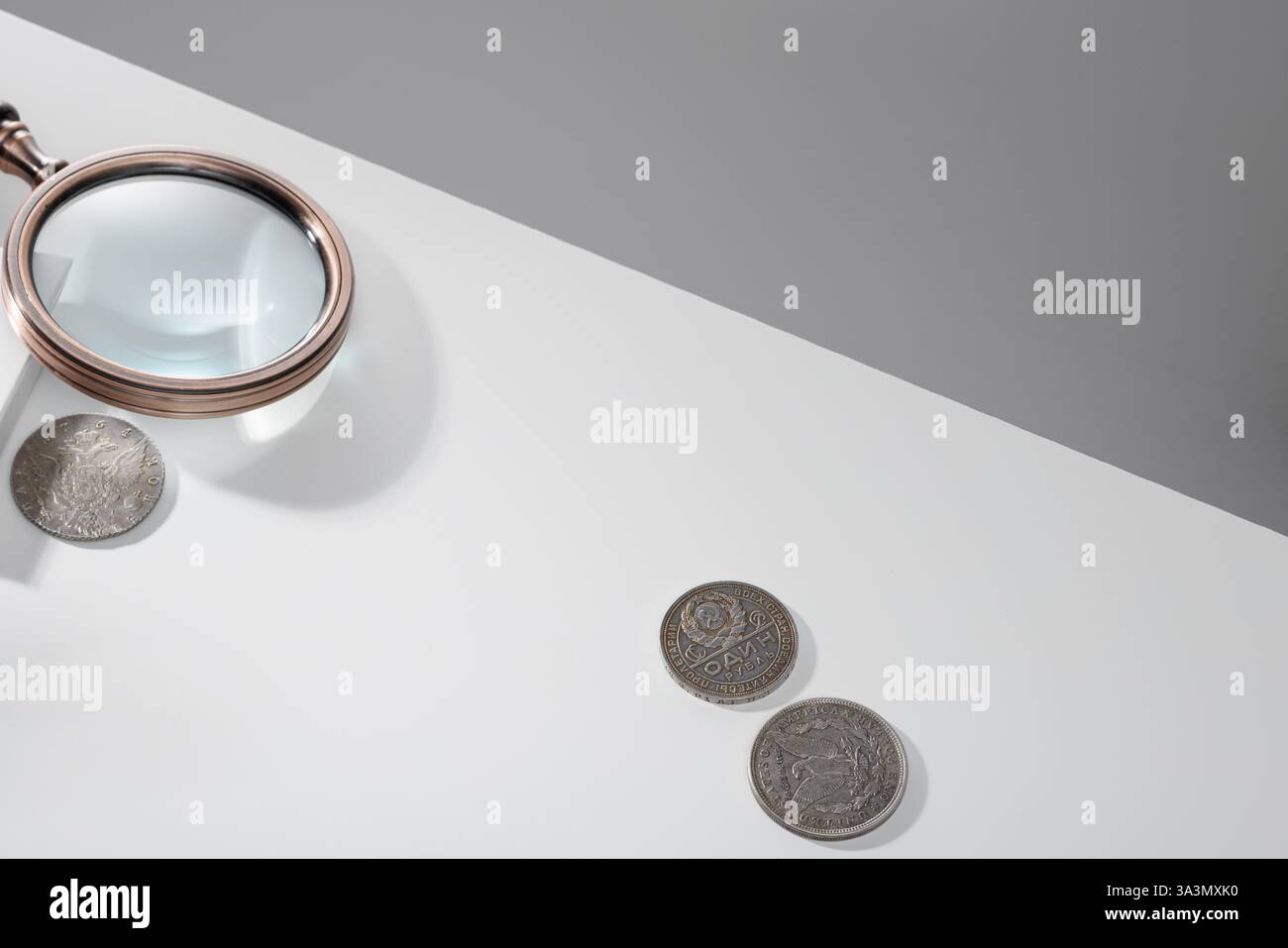 Numismatics. Ancient collectible coins and magnifying glass on a white ...