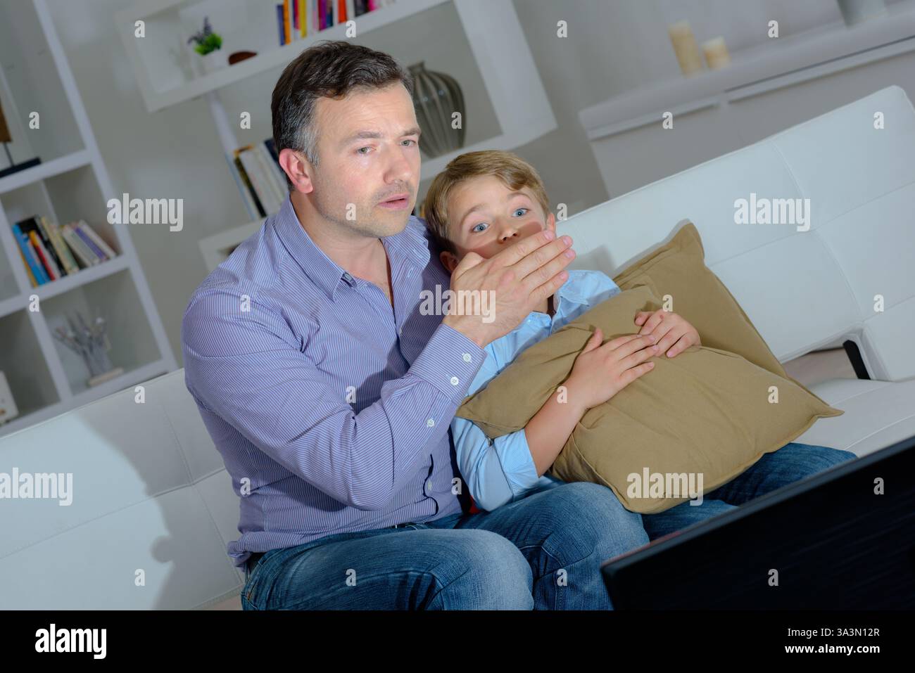 Man covering face of child watching television Stock Photo - Alamy