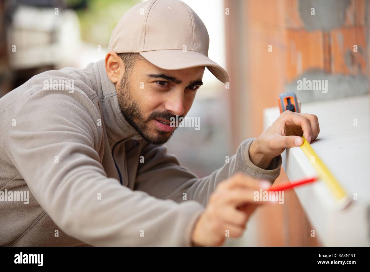 male builder measuring window sill Stock Photo - Alamy