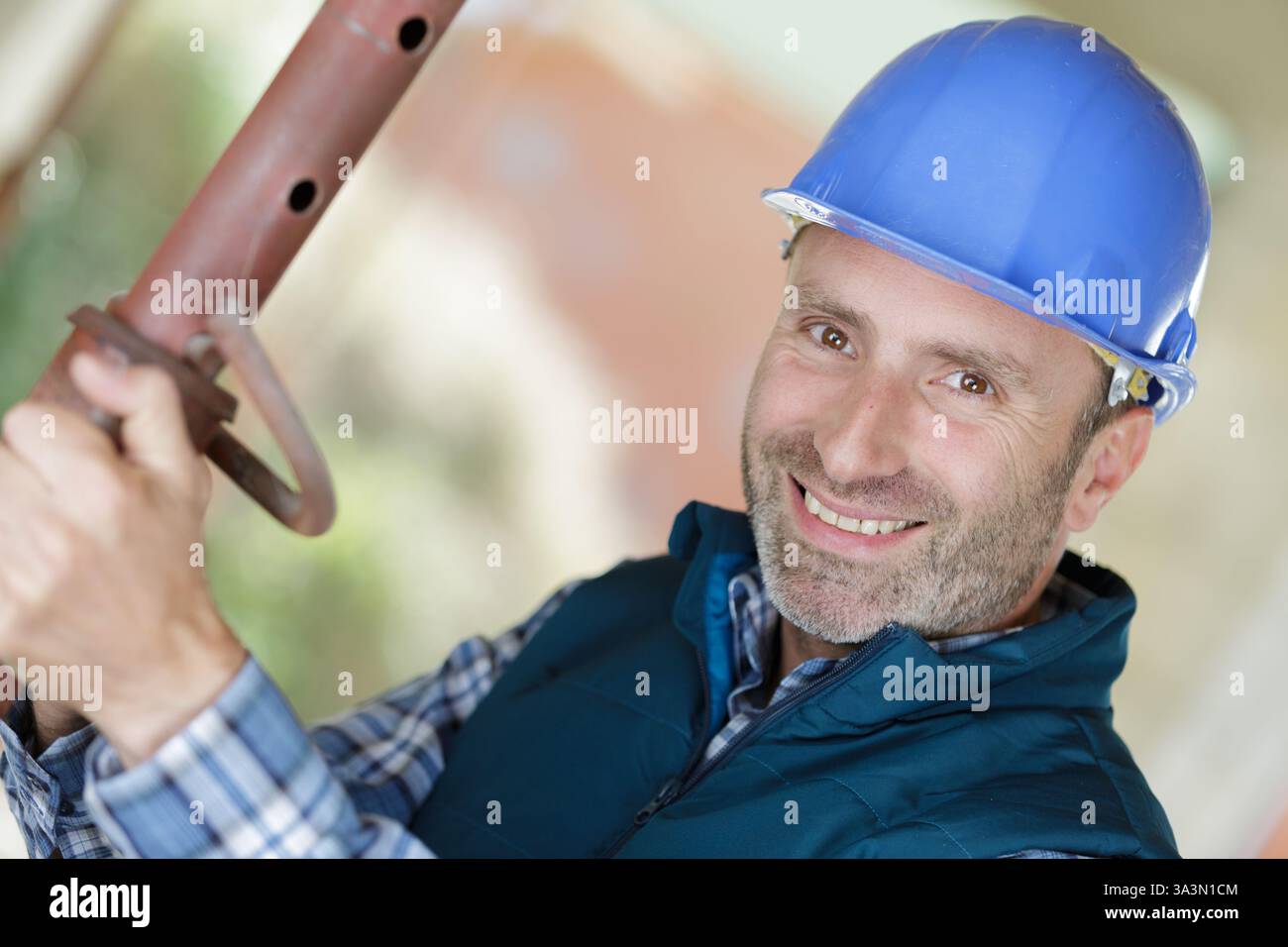 happy construction worker on site holding pipe Stock Photo - Alamy
