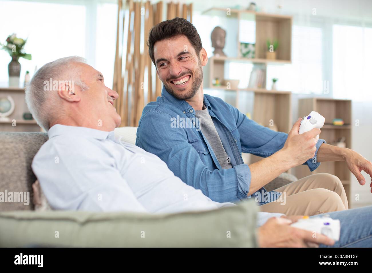 mature son and elderly father playing video game having fun Stock Photo - Alamy