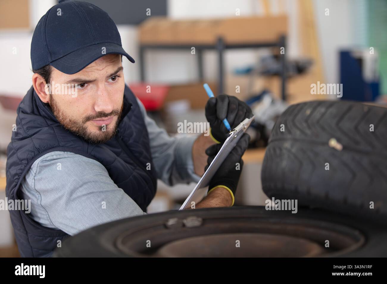 mechanic with clipboard assessing tyres Stock Photo - Alamy