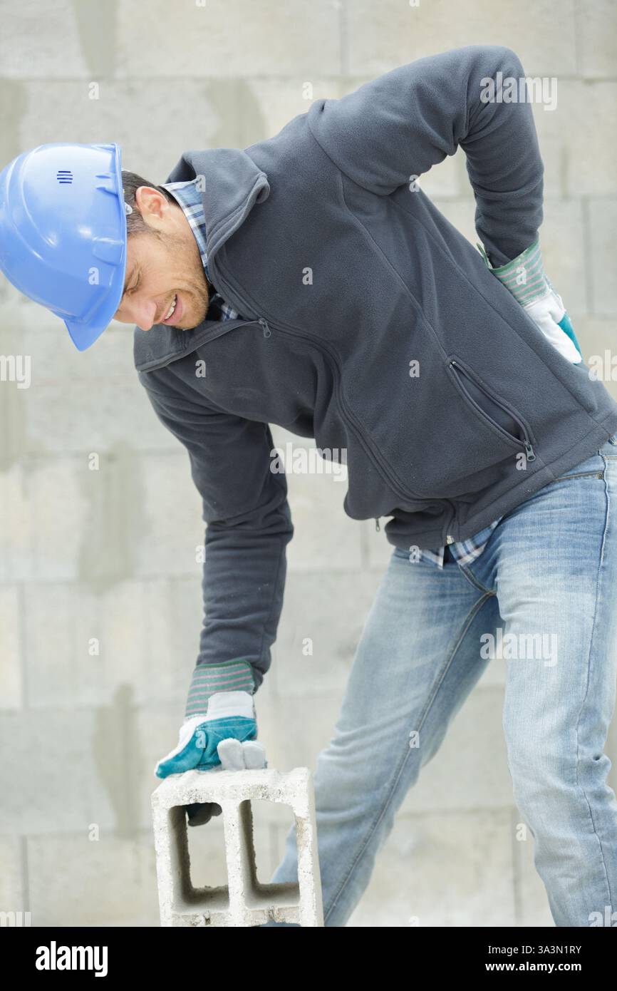 builder touching painful stretched lower back because of physical work ...