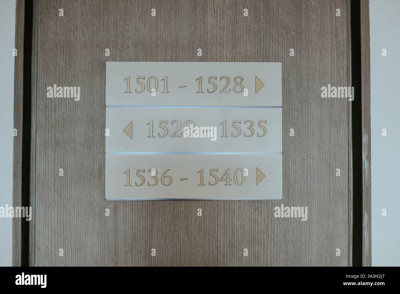 A modern room directory displaying room ranges on a sleek sign affixed ...