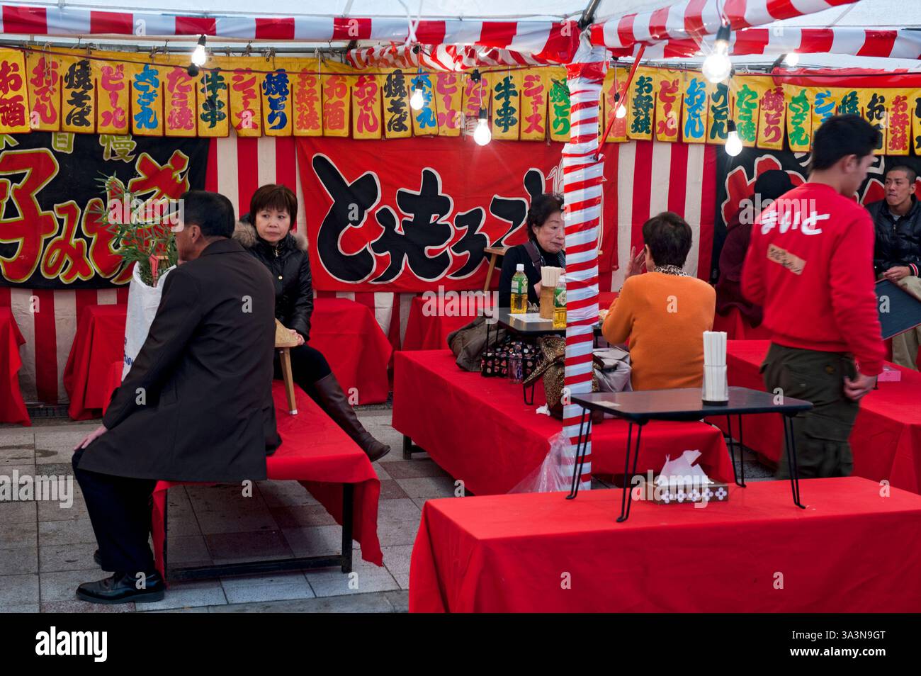 Customers sit at low tables on red platforms at the Maito outdoor ...