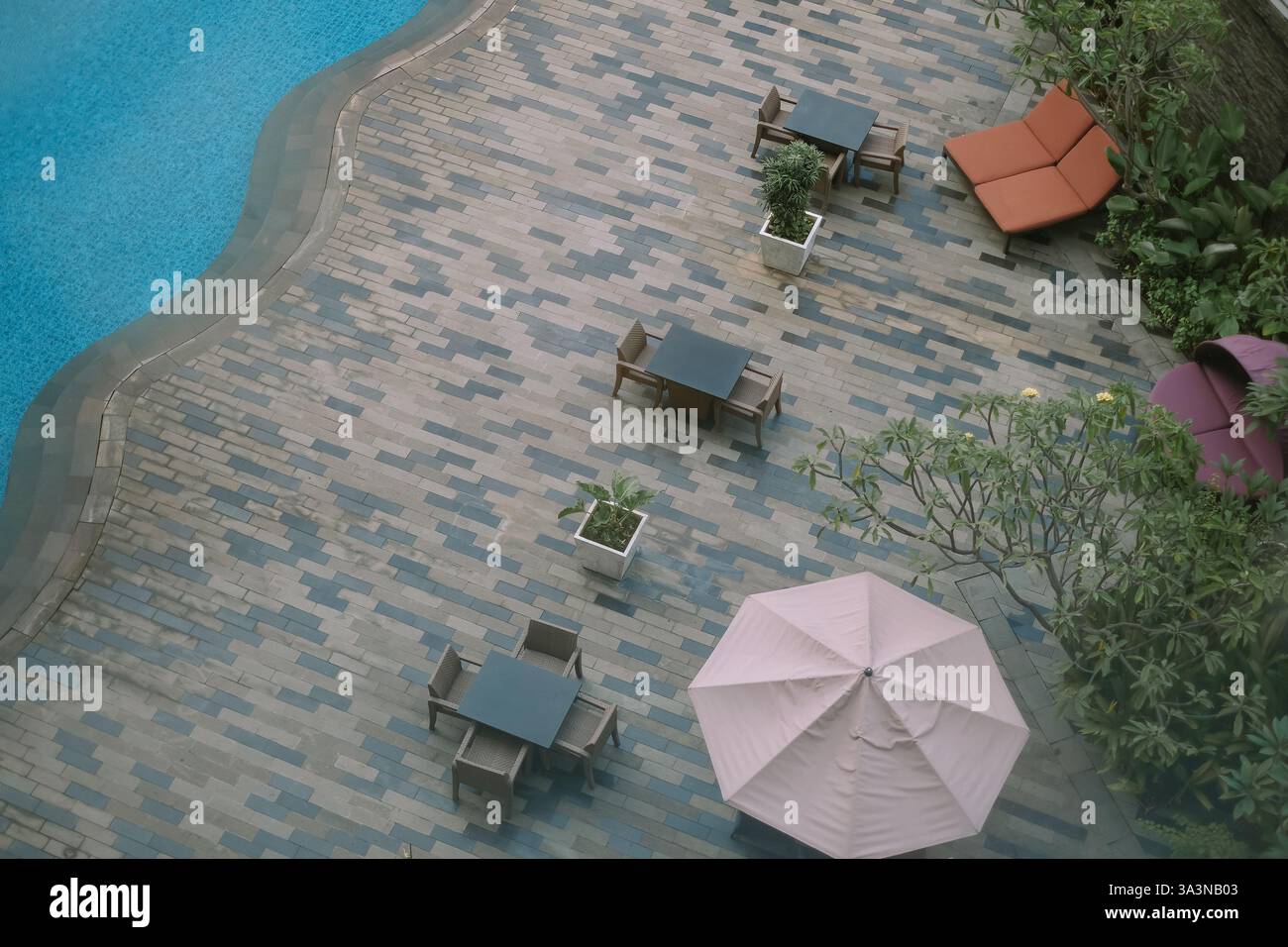 Aerial view of a serene and stylish hotel courtyard featuring a swimming pool, cozy patio ...