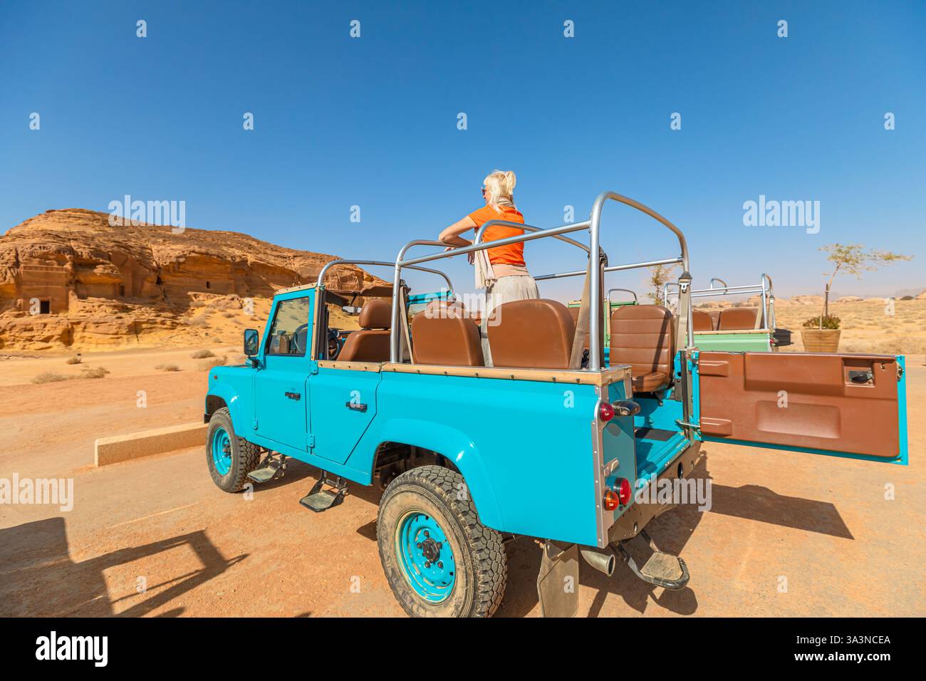 Blonde tourist standing at Jabal Al-Ahmar on a vintage 4x4 car ...