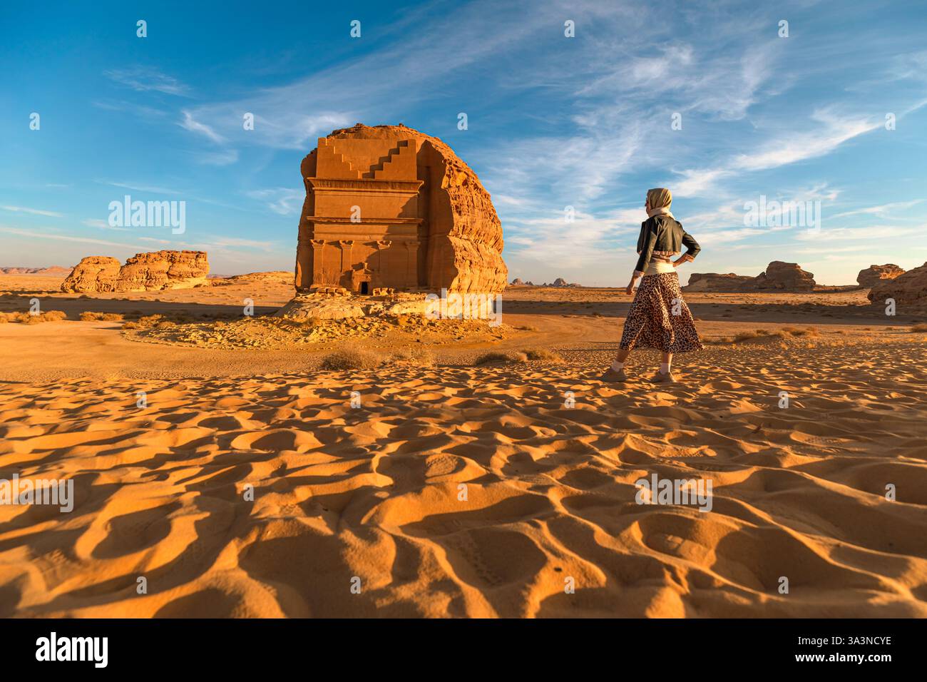 Blonde tourist walking in the desert, admiring the monumental Qasr Al ...