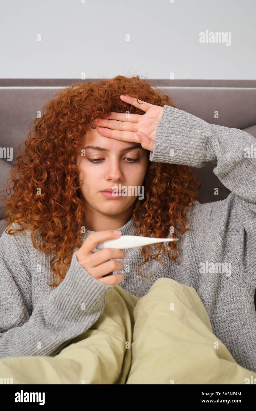 Sick woman is lying in bed and checking her body temperature Stock ...